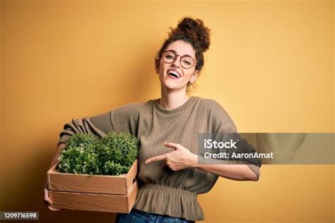 곱슬 머리와 피어싱 나무 상자를 들고 식물과 젊은 아름다운 정원사 여자는 손과 손가락으로 가리키는 매우 행복 가리키기에 대한 스톡 사진 및 기타 이미지 Istock