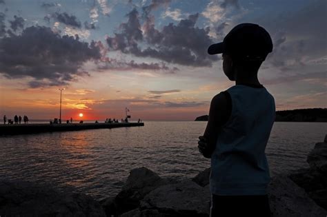 Premium Photo Boy Looking At Sea Against Sky During Sunset