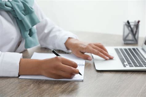 Woman Writing Notes While Using Laptop At Wooden Desk Indoors Closeup Stock Photo Image Of