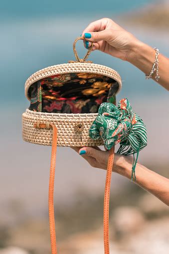바다 바탕에 세련 된 세련 된 등나무 가방 실크 스카프와 여자 손 발리 인도네시아의 열 대 섬입니다 등나무 핸드백 및 실크