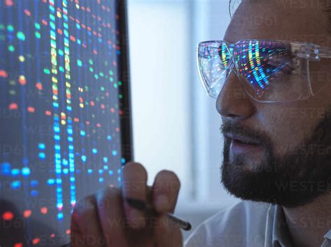 scientist wearing protective eyeglasses analyzing dna data on computer