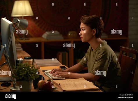 Side View Of Female Asian Babe Typing On Computer Keyboard While Doing Homework Late At Night