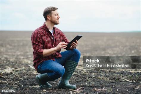 농부는 파종하기 전에 토양의 품질을 확인합니다 들판에 태블릿을 든 여자 농부가 손에 흙을 들고 있다 소녀 농경 학자는 파종 곡물의 품질을 확인합니다 비즈니스 우먼은 자신의