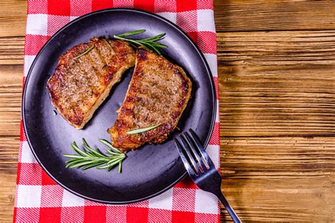 구운 스테이크와 로즈마리 나뭇가지를 나무 테이블에 놓은 접시 맨 위 보기 0명에 대한 스톡 사진 및 기타 이미지 0명 건강에 좋지 않은 음식 검은색 Istock