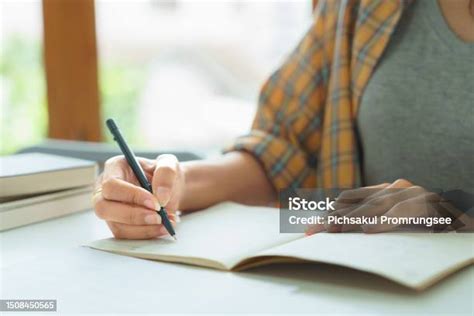 แนวคิดการศึกษาและการรู้หนังสือสาวนักศึกษาวิทยาลัยอ่านแผ่นบทเรียนและจดบันทึกบนสมุดบันท ภาพสต็อก