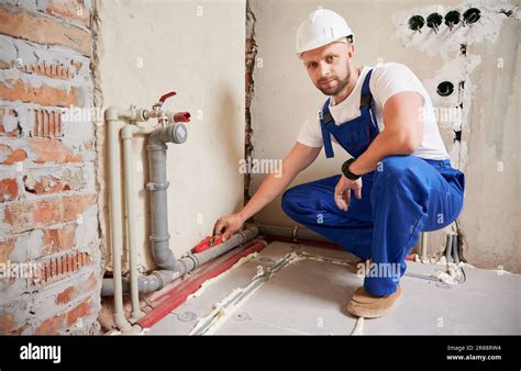 Male Plumber Using Spirit Level Tool While Installing Pipe System At Home Looking To The Camera