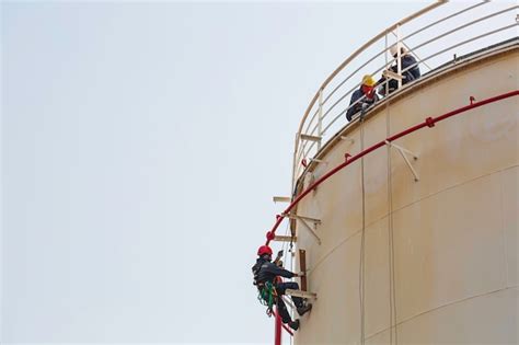 남성 작업자 로프 액세스 산업 높이 탱크 오일 착용 하네스 헬멧 안전 장비 로프 액세스 두께 탱크에서 작업 프리미엄 사진