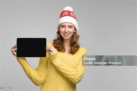 회색 배경에 스튜디오에서 노란색 스웨터와 크리스마스 모자에 좋은 젊은 여성 태블릿과 개념 감정에 대한 스톡 사진 및 기타 이미지 Istock