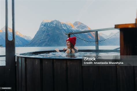 노르웨이의 겨울 피요르드의 경치를 볼 수 있는 온수 욕조에서 휴식을 취하는 빨간 모자를 쓴 여성의 측면 모습 12월에 대한 스톡 사진 및 기타 이미지 Istock