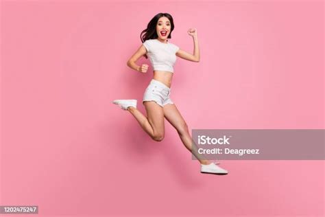 그녀의 전체 길이 몸 크기보기 그녀의 좋은 찾고 매력적인 꿈꾸는 즐거운 쾌활한 쾌활한 물결 모양의 머리 소녀 점프 재미 실행 을 통해 고립 된 핑크 파스텔 색상 배경