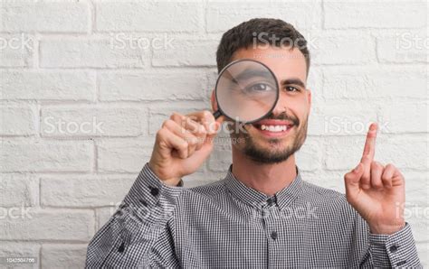 벽돌 위에 젊은 성인 남자는 아이디어 돋보기 유리 놀된을 사용 하 여 벽 또는 행복 한 얼굴 넘버 원 가리키는 손가락 질문 가리키기에 대한 스톡 사진 및 기타 이미지