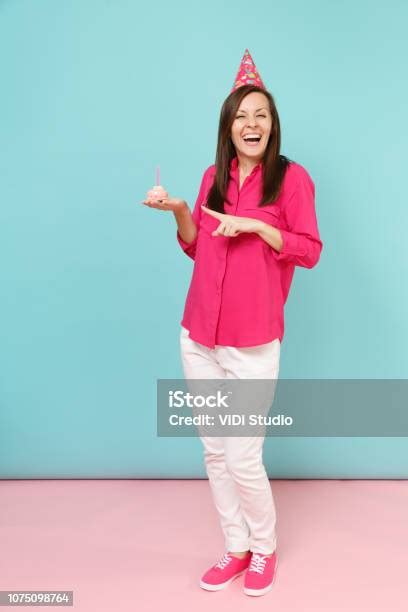 전체 길이 세로 여자 장미 셔츠 블라우스 백색 바지 컵 케 잌은 밝은 핑크 블루 파스텔 벽 배경 스튜디오에 고립 된 포즈와 생일 모자 패션 라이프 스타일 개념입니다 복사