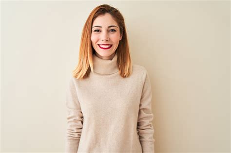 얼굴에 행복하고 시원한 미소와 고립 된 흰색 배경 위에 서 우아한 터틀넥 스웨터를 입고 빨간 머리 여자 운이 좋은 사람 겨울에 대한 스톡 사진 및 기타 이미지 Istock