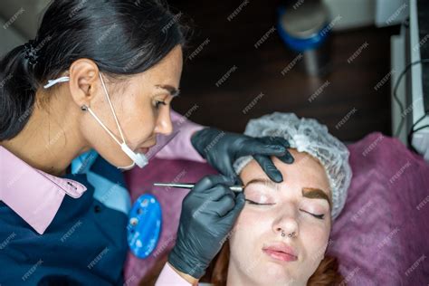 Premium Photo Procedure Of Eyebrow Microblading A Master In Black Gloves Is Doing A Blending
