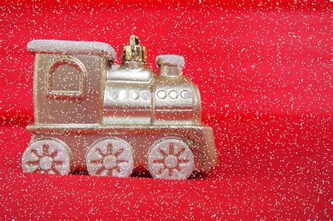 빨간색과 분홍색 그라데이션 배경에 황금 장난감 기차 기관차 새해 또는 크리스마스 카드 기차에 고드름과 눈 텍스트를 위한 여유 공간 공간을 복사합니다 떨어지는 눈송이 12월에