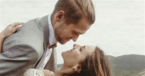 세련 된 신랑은 태양 빛과 미소 낭만적 인 순간 Boho 결혼식 커플 놀라운 전망을 가진 산에서 호화로운 결혼식에서 행복한 신부를 안고 행복 합니다 사진