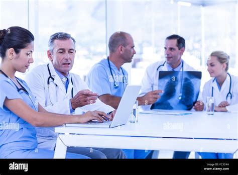 Doctors Using Computer Whiles Theirs Colleagues Looking At Xray Stock