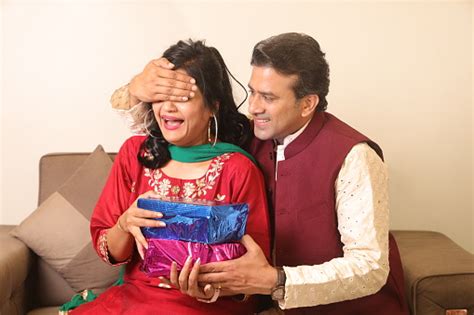 행복한 인도 남자는 사리에서 인도인 아내를 위해 깜짝 선물을 가져옵니다 둘 다 디왈리 축제에 인도 민족 의상을 입고 있습니다 2명에 대한 스톡 사진 및 기타 이미지 Istock