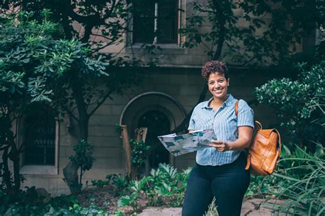 배낭과 종이 지도를 들고 세계를 탐험하기 위한 여행 휴가를 즐기는 쾌활한 여성 관광객의 절반 길이 초상화 도시 공원에서 카메라를 향해 웃고 있는 위치 종이를 가진 행복한