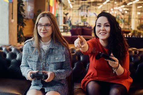 Two Girlfriends Play Video Games Hold Joysticks In Their Hands The Guy Lost Console Games