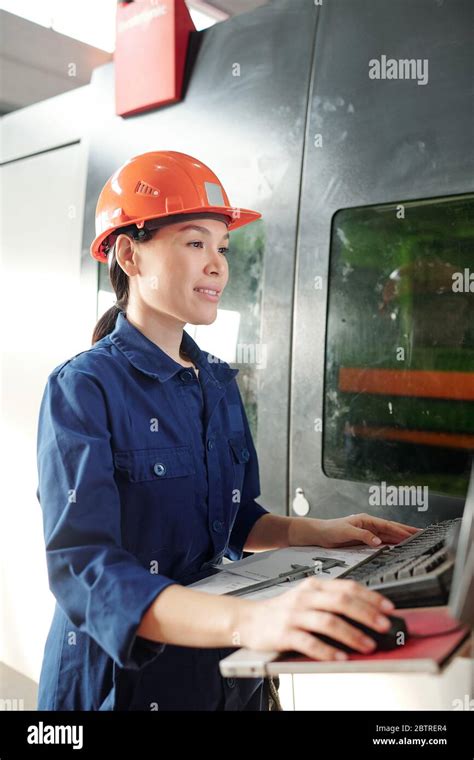 Smiling Young Asian Woman In Hardhat Operating Cnc Machine While Smiling Young Asian Woman In Hardhat Operating Cnc Machine While