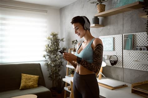 백인 여성이 가정 운동을 위해 휴대 전화로 재생 목록을 준비합니다 20 24세에 대한 스톡 사진 및 기타 이미지 20 24세 Brand Name Online