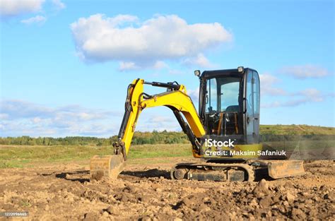 필드 나 숲에서 지구를 파고 미니 굴삭기 집 건설 중에 지하 하수도 파이프를 깔고 있습니다 가스 파이프라인 또는 석유 파이프라인을 위한 참호 발굴 소형 굴삭기에 대한 스톡