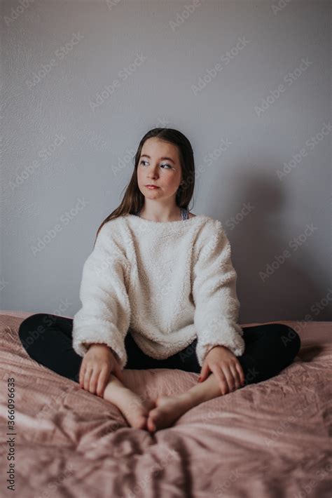 Vertical Portrait Of Tween Girl Sitting On Bed Looking Away Stock Photo Adobe Stock