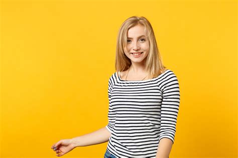 서 있는 줄무늬 옷에 예쁜 젊은 여자 미소의 초상화 스튜디오에서 노란색 주황색 벽 배경에 고립 된 찾고 카메라 사람들은 진심으로 감정 라이프 스타일 개념입니다 복사 공간을