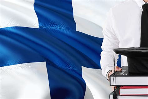 성공적인 핀란드어 학생 교육 개념입니다 핀란드 국기 배경 위에 책과 졸업 모자를 들고 대학교에 대한 스톡 사진 및 기타 이미지 대학교 핀란드 교사 교육 관련 직업