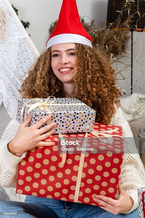 크리스마스 선물 상자를 가진 젊은 긍정적 인 여자는 니트 풀오버와 산타 모자를 착용 겨울에 대한 스톡 사진 및 기타 이미지