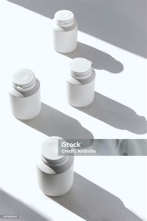 최소한의 스타일 구성은 보충 비타민 그림자가 있는 햇볕이 잘 드는 배경에 알약을 위한 흰색 플라스틱 병으로 만들어졌습니다 캡으로 포장하는 용기 세트 약국 및 의학 개념 생활