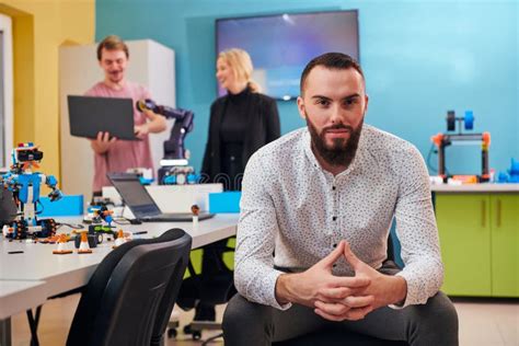 A Man Sitting In A Robotics Laboratory While His Colleagues In The Background Test New Cutting