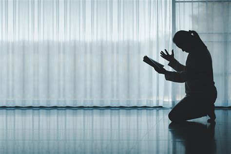 일몰 시간에 현대 교회에서 무릎을 꿇고 기도하는 여자의 실루엣 하느님께 드리는 여성 가톨릭 기도 예배는 믿음으로 새벽에 가정에서 더 나은 삶을 기원합니다 무릎을 꿇고 있는