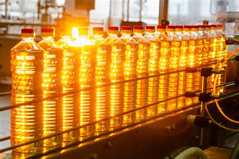 해바라기 기름 올리브 오일 흰색 코트를 입은 공장 직원은 컨베이어 벨트에 손에 기름 한 병을 들고 있습니다 석유 생산 0명에 대한 스톡 사진 및 기타 이미지 Istock