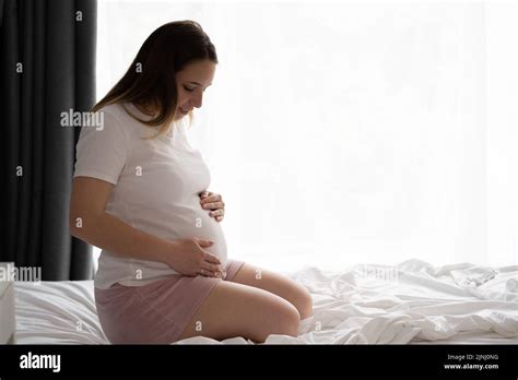 Attractive Pregnant Woman Sitting In Bed And Holding Her Belly Bedroom