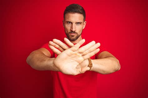 빨간 고립 된 배경 거부 표정 을 건너 팔과 손바닥을 통해 캐주얼 티셔츠를 입고 젊은 잘 생긴 남자는 부정적인 기호 화가 얼굴을하고 T 셔츠에 대한 스톡 사진 및 기타