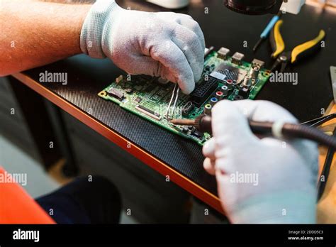 Technician Soldering Circuit Board Of Electrical Component At Workbench