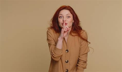 Premium Photo Young Woman Presses Index Finger To Lips Makes Silence