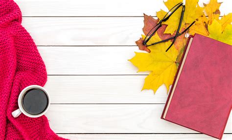 컵 커피 뜨개질을 한 스카프와가 닫힌 책 백색 나무 테이블에 나뭇잎 최고의 볼 수 있습니다 텍스트를 위한 공간입니다 꼭대기에