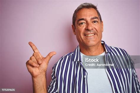 잘 생긴 중년 남자 를 입고 줄무늬 셔츠 위에 서 고립 된 분홍색 배경 매우 행복 가리키는 손과 손가락 으로 측면에 가리키기에 대한 스톡 사진 및 기타 이미지 Istock