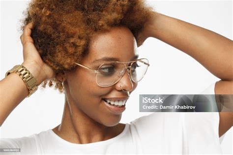 골든 안경 회색 배경 머리를 돌리는 데에 그녀의 머리 감동 절연에 젊은 미소 꼬리 치는 어두운 피부 아프리카계 미국인 여자의 가로 근접 촬영 얼굴만 T 셔츠에 대한 스톡
