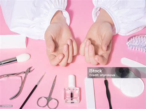 네일 살롱은 여성의 깔끔한 손과 분홍색 배경의 갓 손질된 손톱을 닫습니다 가위 집게 핀셋과 같은 매니큐어 도구를 사용한 미용 및 관리 산업 개념 매니큐어 미용술에 대한 스톡