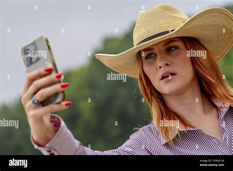 A Beautiful Redhead Model Uses Her Cellphone While Posing In A Country