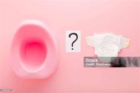 밝은 분홍색 테이블 배경에 아기 변기와 흰색 부드러운 기저귀 사이의 물음표 카드 파스텔 색상 근접 촬영 개념 아기가 변기로 가서 기저귀에 작별 인사를하는 방법을 배울 수