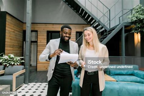 성공적인 웃는 매력적인 백인 사업가와 아프리카 계 미국인 사업가금융 논문과 함께 작업하고 비즈니스 전략에 대해 논의 현대 사무실에 서 기업 문화에 대한 스톡 사진 및 기타