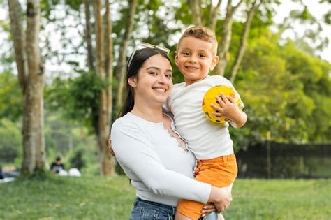 Belle Fille Latina Tenant Son Fils Tandis Que Le Gar On Tient Une Balle Dans Ses Mains Photo