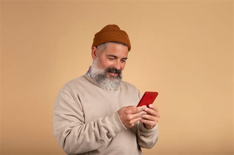 수염이 있는 남자가 전화로 Sms를 읽는다 베이지 색 벽에 스튜디오 촬영 스튜디오 촬영에 대한 스톡 사진 및 기타 이미지 스튜디오 촬영 전화 성년 남자 Istock