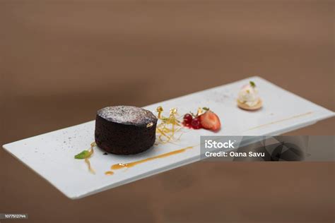 고급 스러운 디저트 브라 우 니 바닐라 아이스크림에는 마카롱 딸기 민트 배치와 함께 장식 된 금과 Leafs Caramelized 설탕흰 접시 갈색 배경 갈색에 대한 스톡