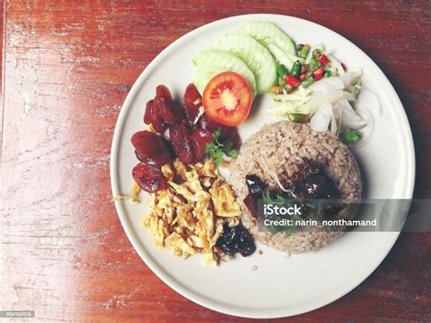 양념 소시지 계란의 슬라이드 나무 테이블에 흰 접시에 달콤한 돼지고기와 새우와 밥 Kao Cluk 카 파이 라는 태국어 붙여넣기 소스를 혼합 태국 음식입니다 빈티지 톤